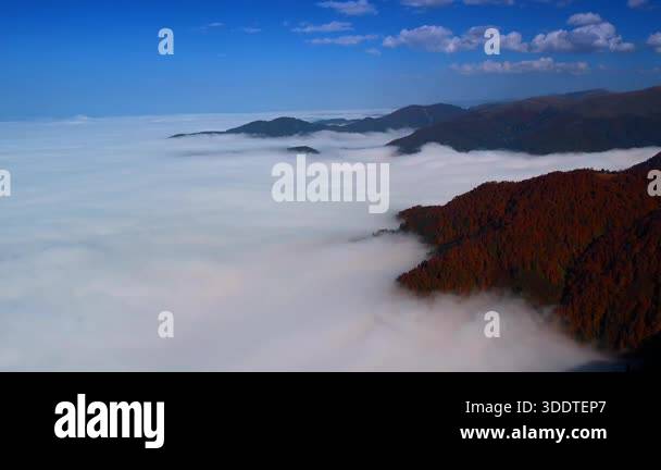 White cloudscape stretching among the mountains. Aerial view on the ...