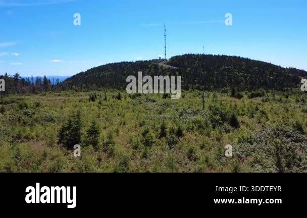 We ascend above a verdant mountain topped with communication antennas ...