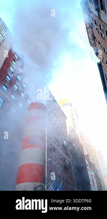 White smoke rises form a pipe outdoors. Street of New York with high ...