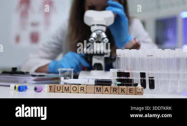 Woman laboratory worker examines blood sample under microscope. Wooden ...