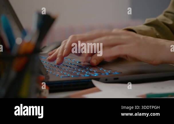 Womans hands rapidly typing on modern laptop with illuminated keyboard ...