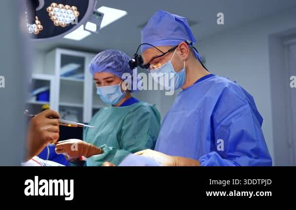 Caucasian medical team in modern surgery room. Nurse passes the ...
