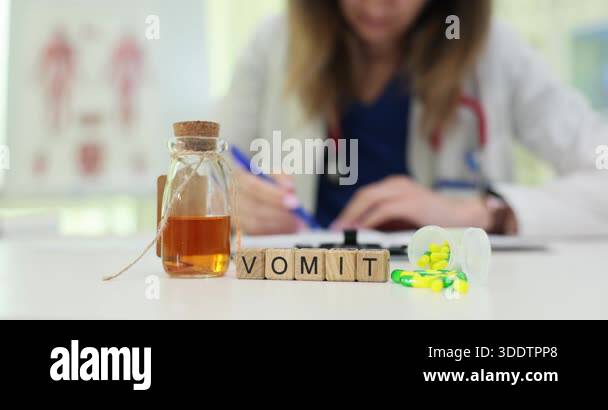 Wooden cubes on clinical desk spell word Vomit as doctor writes plan ...
