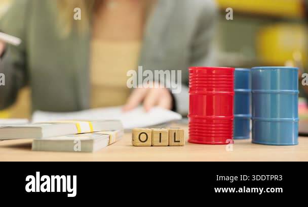Wooden cubes on table spell word Oil while businesswoman stamps ...