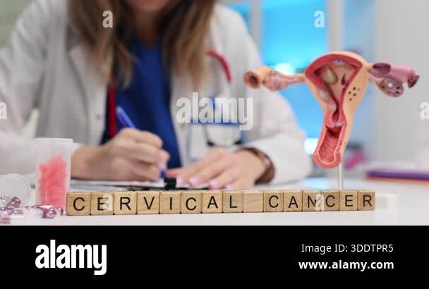 Wooden cubes on table spell words Cervical Cancer while female doctor ...