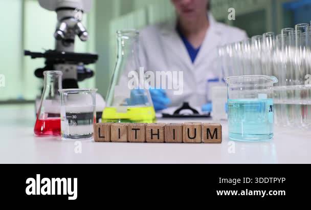 Woman chemist carefully writes down results of lithium analysis. Wooden ...