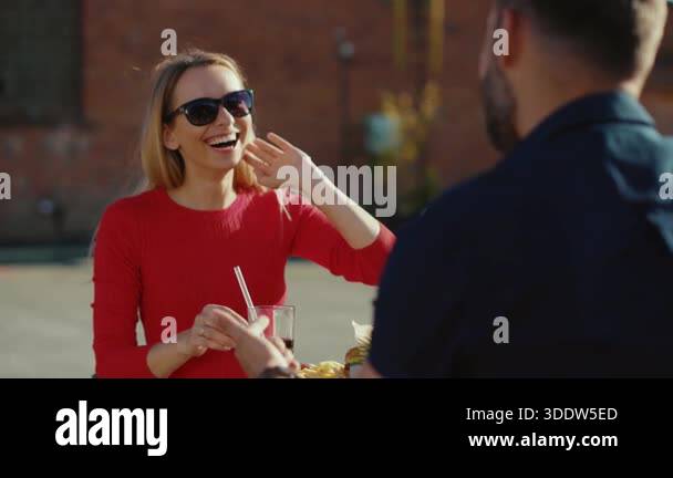 Funny young relaxing man and woman drinking cocktail eating burger in ...
