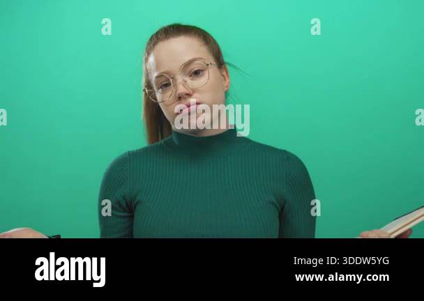 Young woman holds notepad against green studio wall scribbling with ...