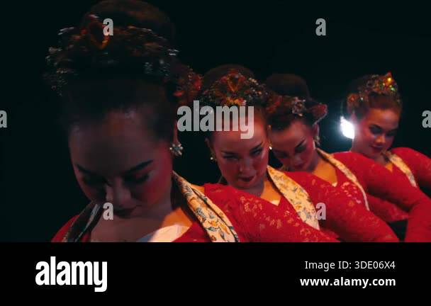 A low-angle close-up of four Indonesian women in traditional red kebaya ...