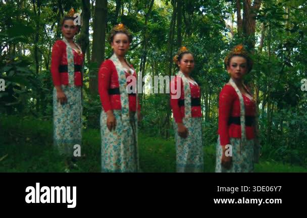 A group of four Indonesian women in red kebayas and batik sarongs stand ...