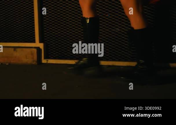 A tilt-up shot reveals a woman in a creepy clown costume leaning ...