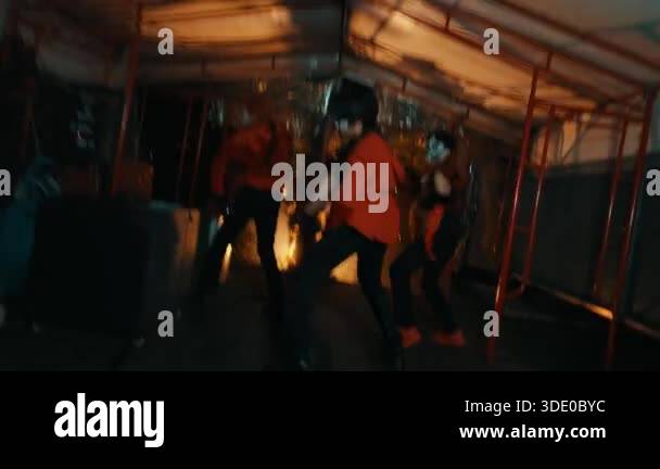 A dynamic, shaky-cam perspective follows three male performers in ...