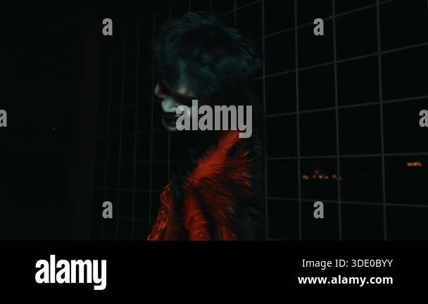 An intense close-up of a male performer in scary gothic clown makeup ...