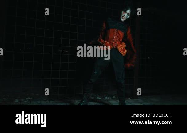 A full shot of a male performer in gothic clown makeup, red fur coat ...