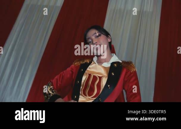 An energetic young Asian woman in a red ringmaster costume dancing ...