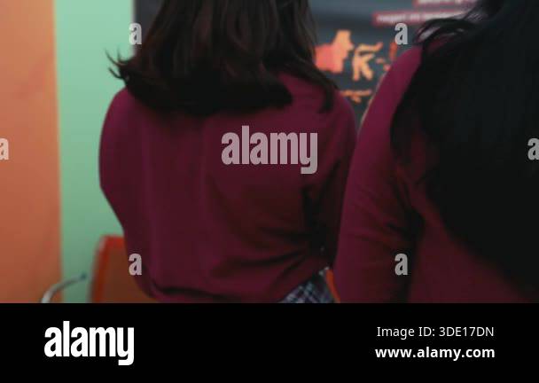 A medium shot of a female high school student in a hoodie and plaid ...