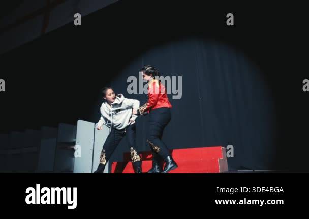 A woman in a white hoodie and another in a ringmaster costume perform a ...