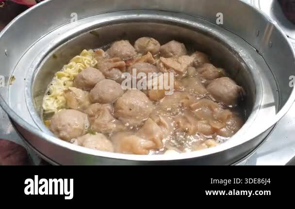 This Indonesian street food features a metal pot filled with simmering ...