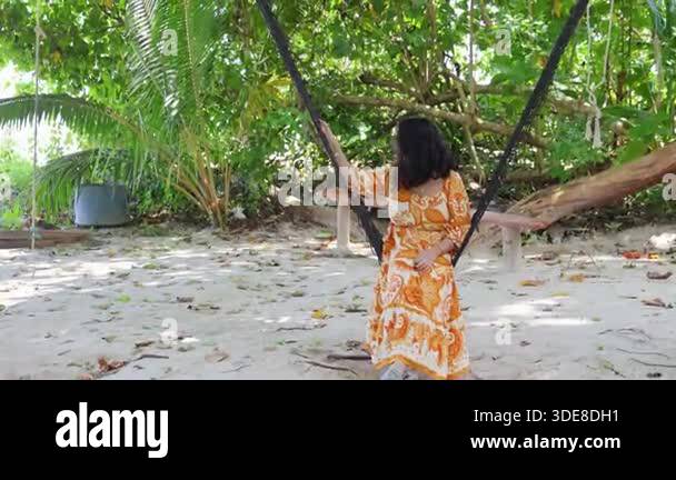 serene resort garden scene with woman on hanging hammock with beach ...