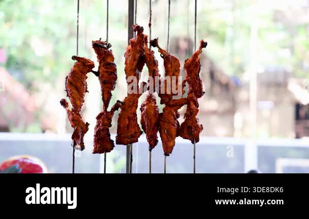 spicy tandoori chicken skewers hanging vertically at restaurant Stock ...