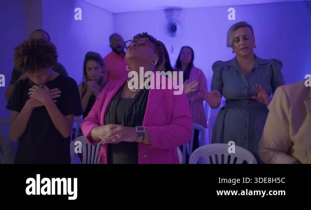 Female preacher with microphone speaking to diverse congregation during ...