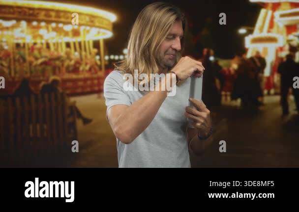 Man grips metal pole on street at night under shimmering carousel ...