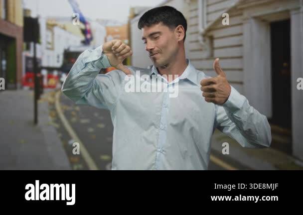 Man makes opposing thumbs up and thumbs down gestures on an urban ...