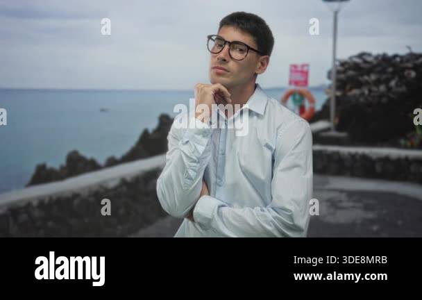 Man wearing glasses and crisp shirt with hand on chin and serious ...