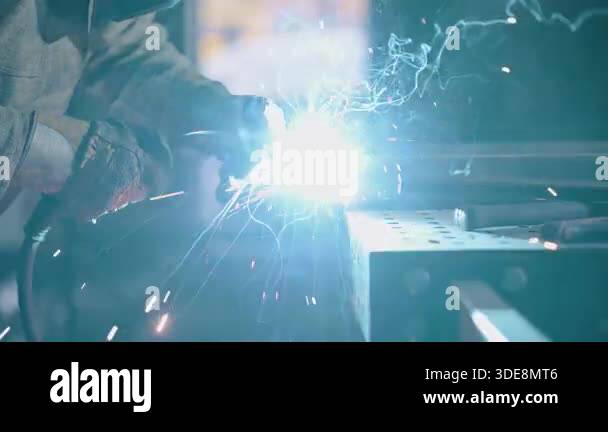 A close-up of a worker welding metal, with bright sparks flying as the ...