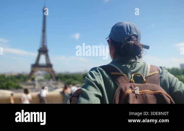 Woman wearing a cap and backpack captures the iconic eiffel tower using ...