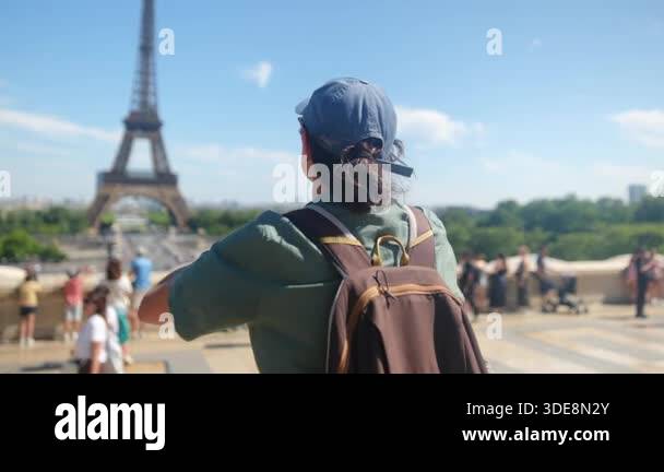 Woman wearing a cap and backpack captures the iconic eiffel tower using ...