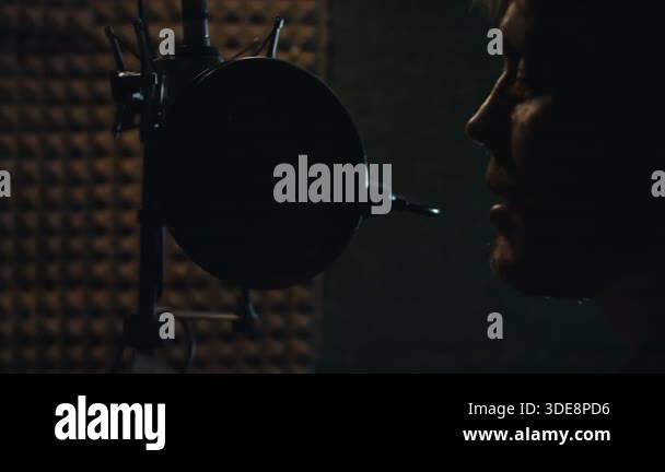 Back view of a male rap singer in headphones singing in a recording ...