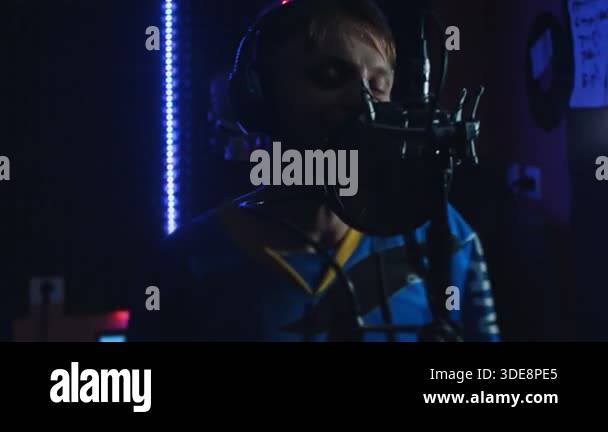 Portrait of handsome male rap singer in headphones recording a song ...