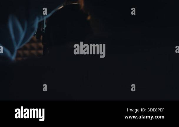 Back view of a male rap singer in headphones recording a new song in a ...