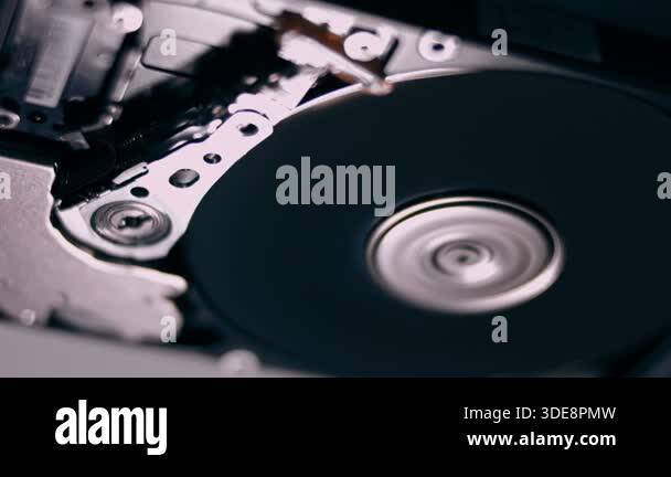 Opened HDD with a spinning magnetic disk and a mechanical arm with head ...