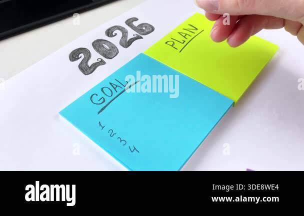 A girl writes down her plan and goals for 2026 on colorful sticky notes ...