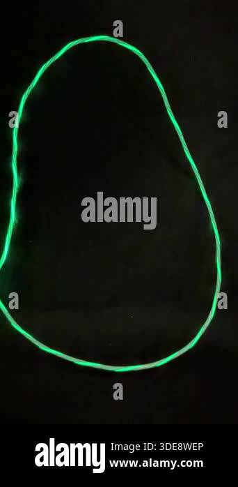 A luminous green loop against a dark background continuously fluctuates ...