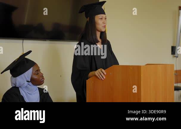 A young woman stands at the lectern and delivers a graduation speech to ...