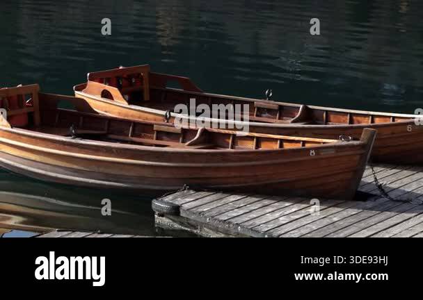 Close-up of a small, narrow brown wooden boat docked perpendicular to a ...