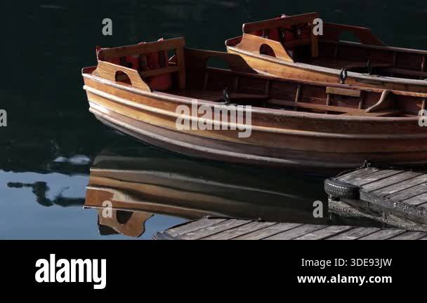 Close-up of a small, narrow brown wooden boat docked perpendicular to a ...