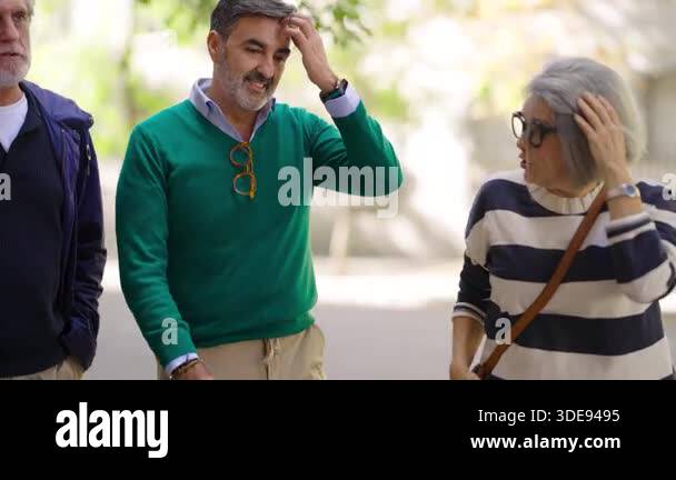 Senior husband and wife walking and talking on a city street. The man ...