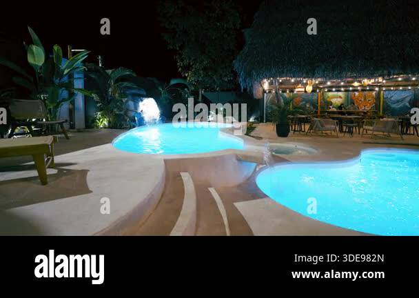 Beautiful swimming pool and jacuzzi illuminated with blue lights at ...