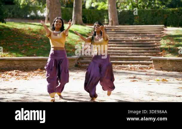 Two young smiling indian women in traditional clothing performing a ...