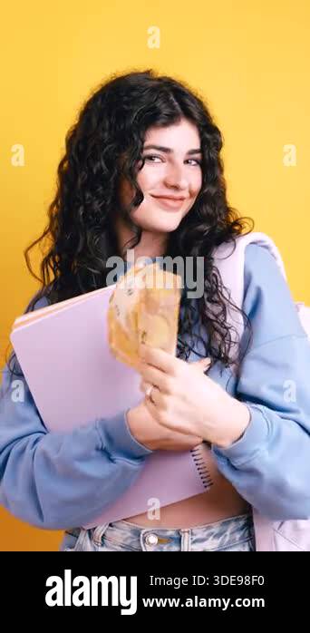 Cheerful female student with a backpack and notebook proudly showing a ...
