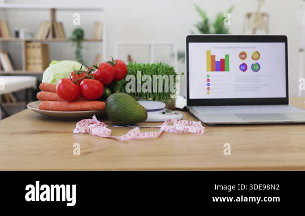 A laptop displays a healthy diet chart next to fresh vegetables and a ...