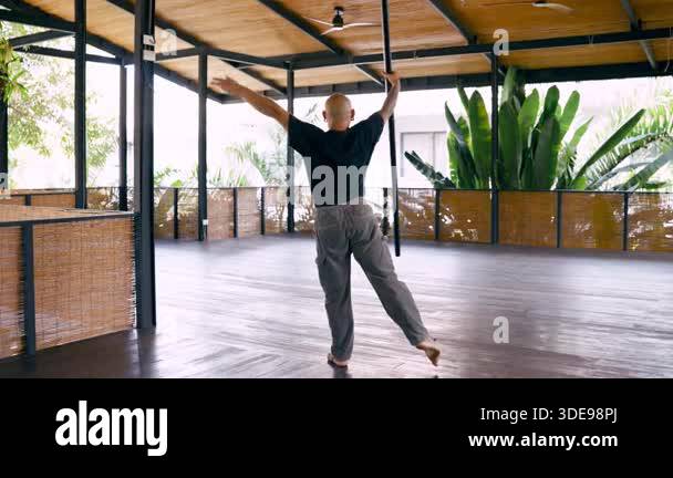 Barefoot man with tattoos performing a fluid, dance like martial arts ...