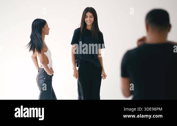 Two female models are posing and laughing while a photographer takes ...