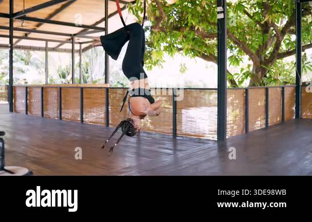 Athletic young woman with tattoos spinning gracefully upside down on an ...