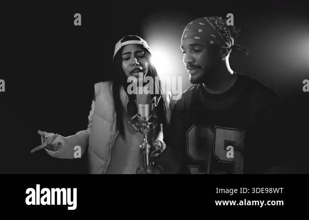 Multiethnic duo singing and dancing energetically into a condenser ...