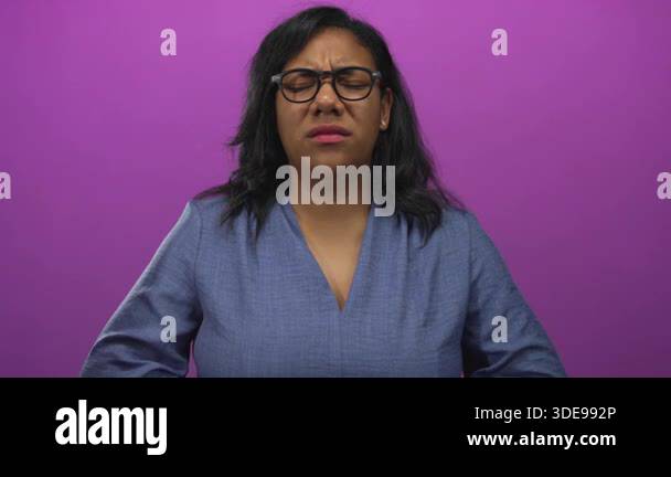African american woman wearing glasses frowns and holds lower back in ...